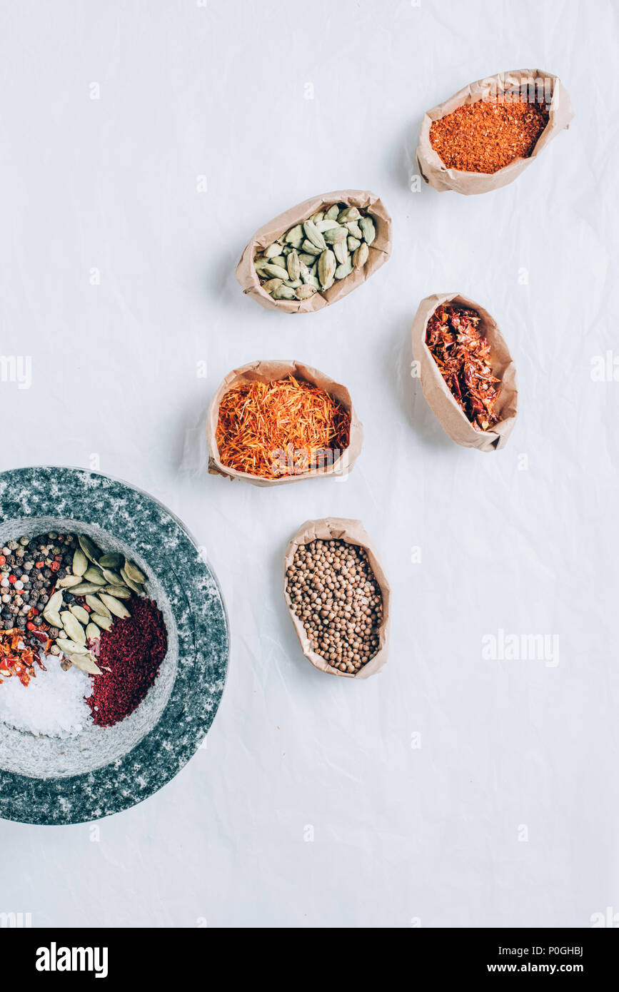 top view of spices in paper bags and mortar on white table Stock Photo ...
