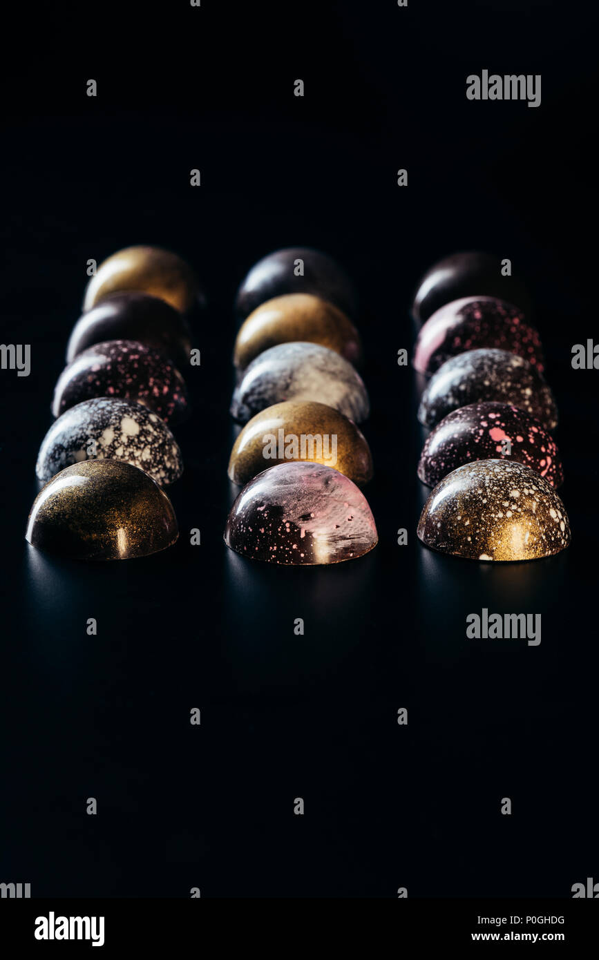 different chocolate candies placed in rows on black background Stock ...