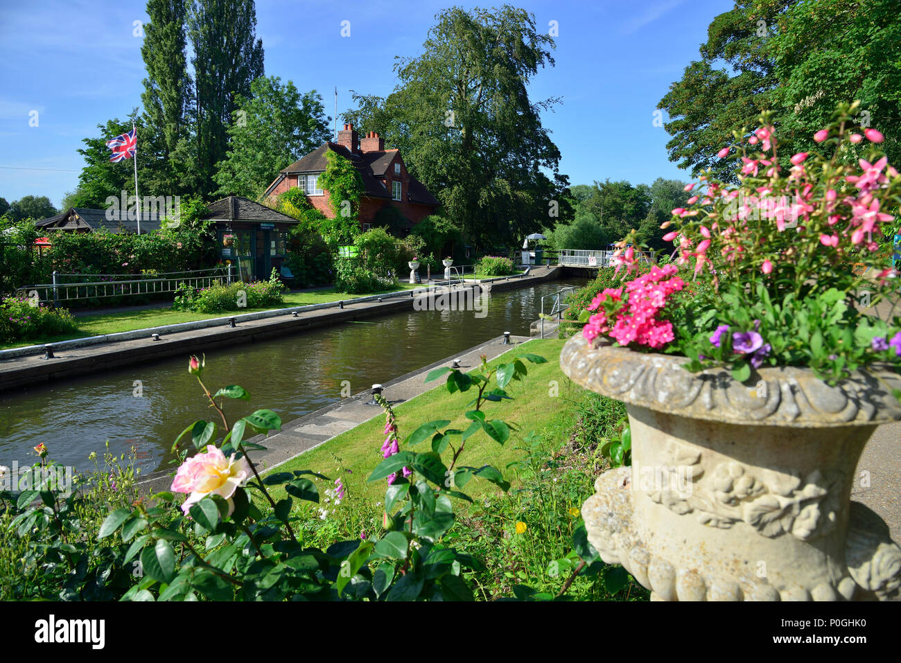 Summer plants flowering at the Sonning Lock with motorboat going ...