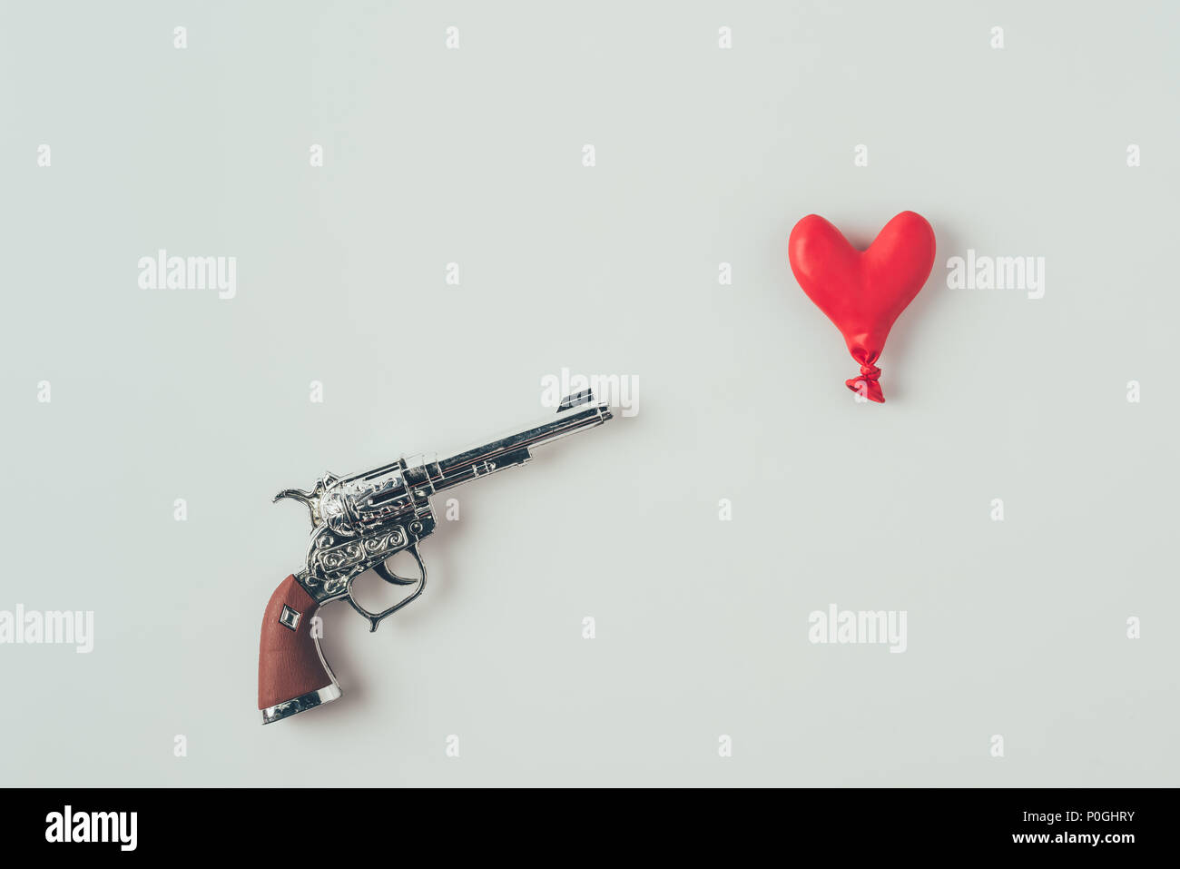 top view of gun barrel aiming at heart shaped balloon isolated on white ...