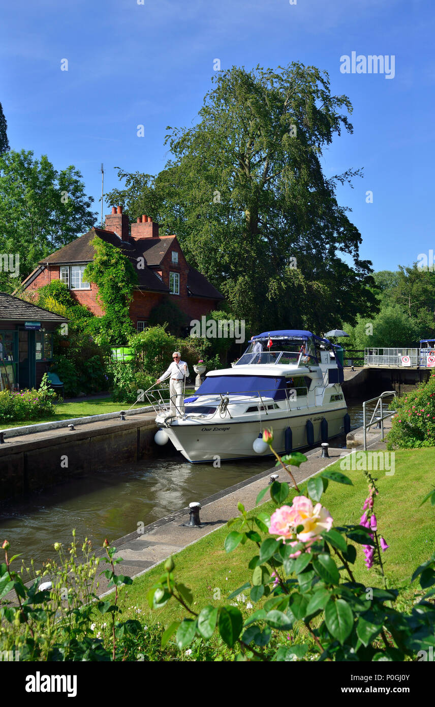 Summer plants flowering at the Sonning Lock with motorboat going ...