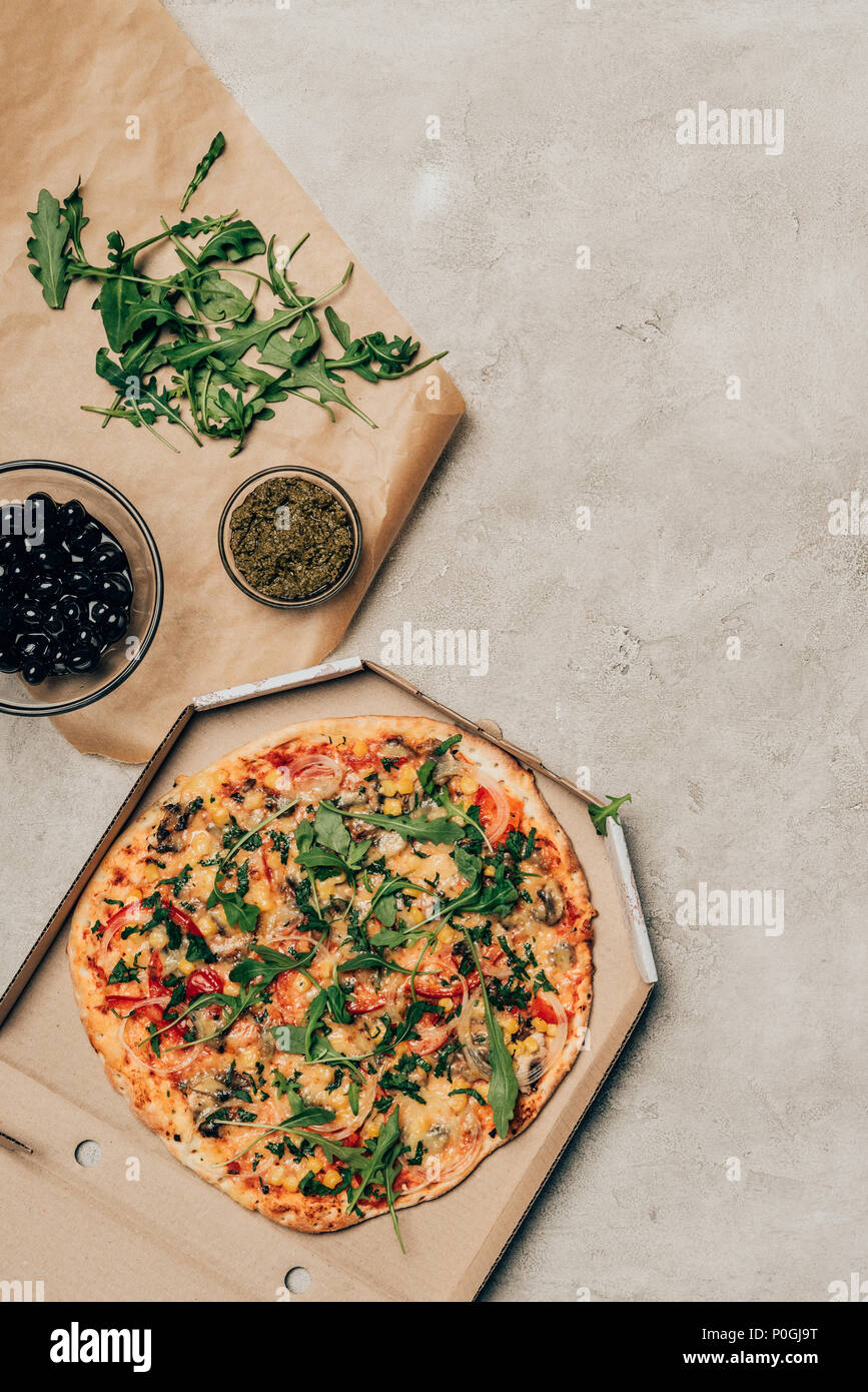 Pizza in cardboard box with toppings on light background Stock Photo ...