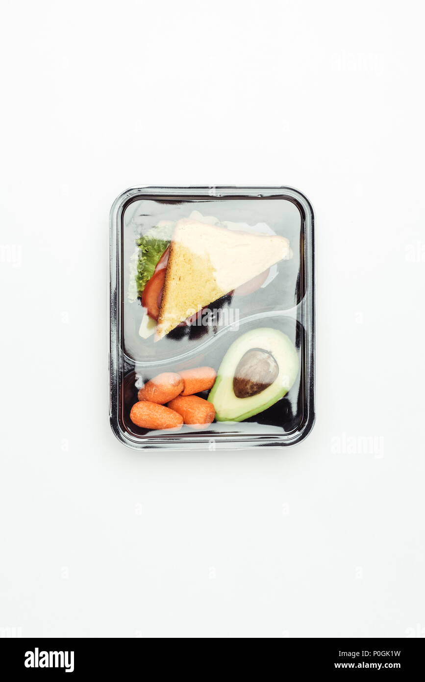 top view of closed plastic lunch box with sandwich and vegetables ...