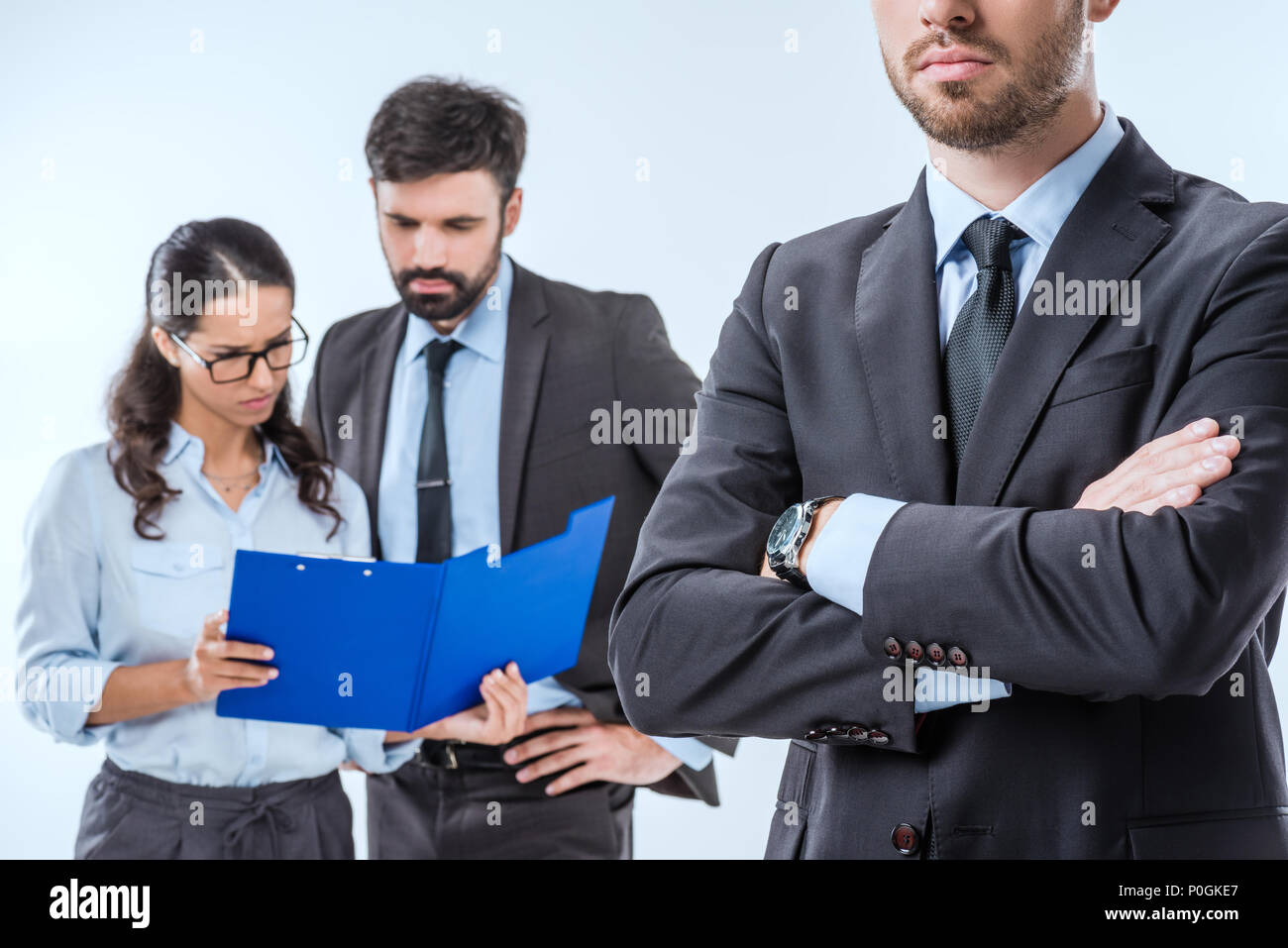 cropped shot of businessman with arms crossed and colleagues discussing ...