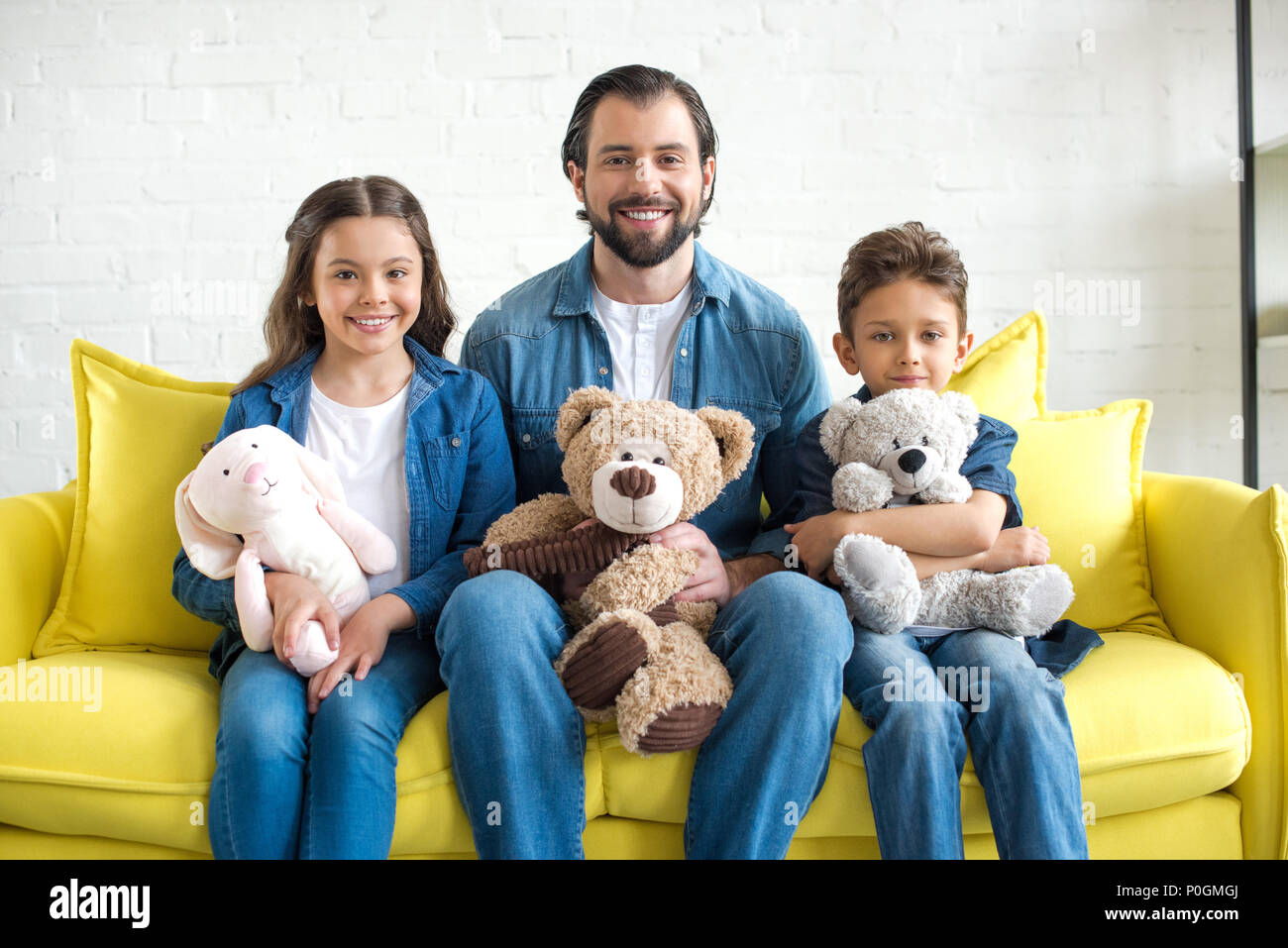 happy father with two adorable kids holding toys and smiling at camera ...