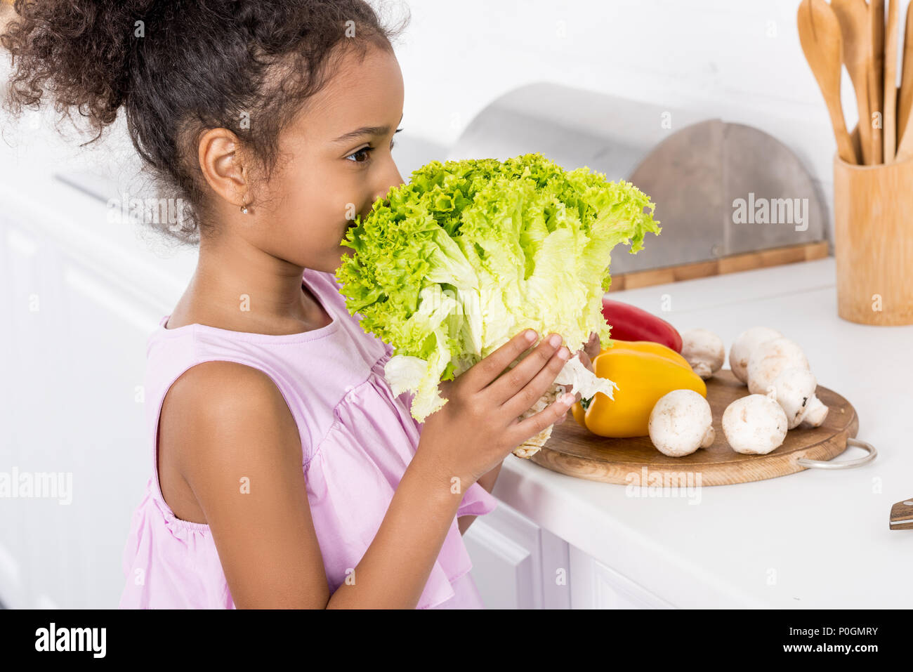 african american child sniffing green lettuce in kitchen Stock Photo ...
