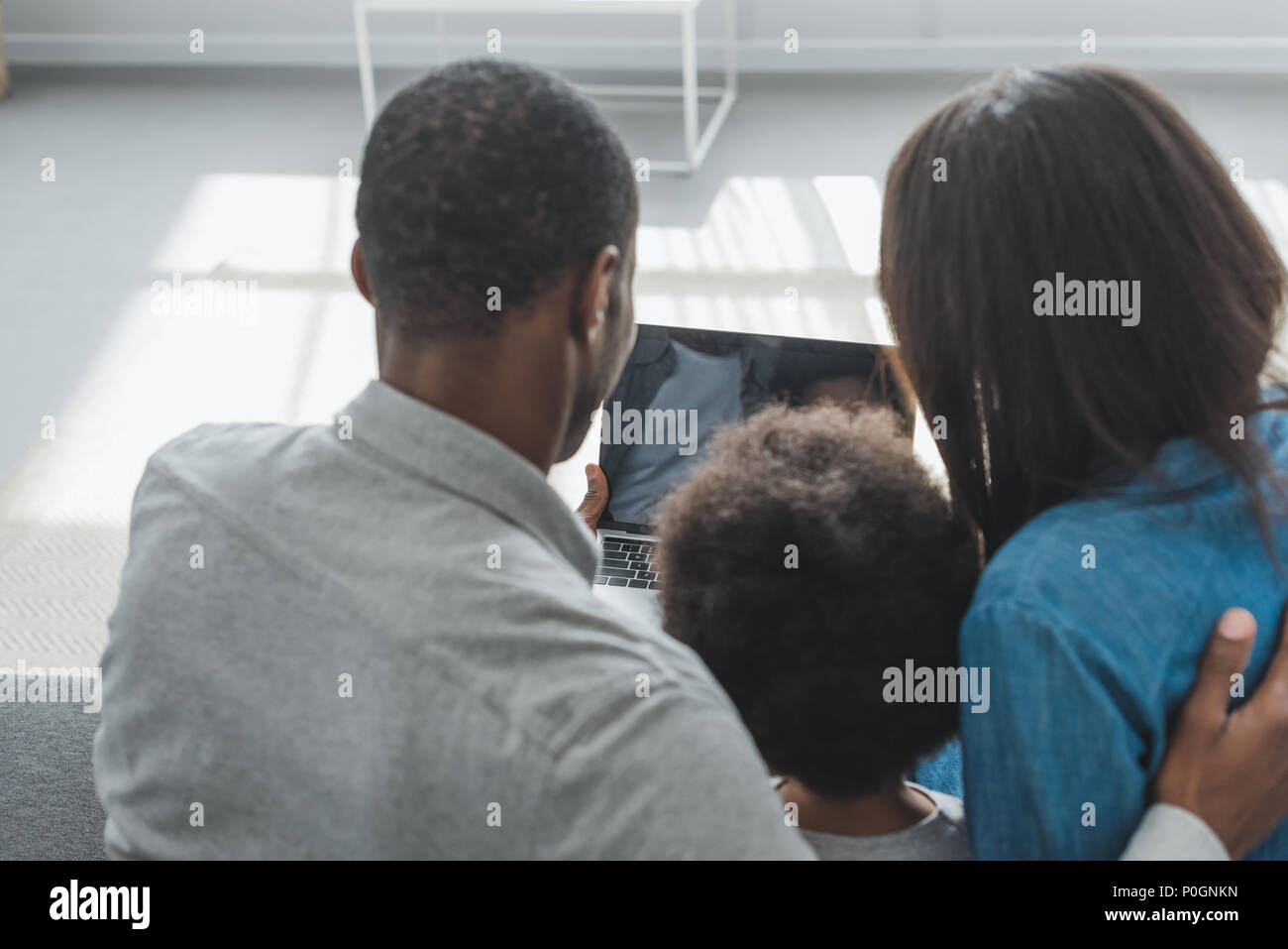 back view of african american parents and son using laptop in living ...