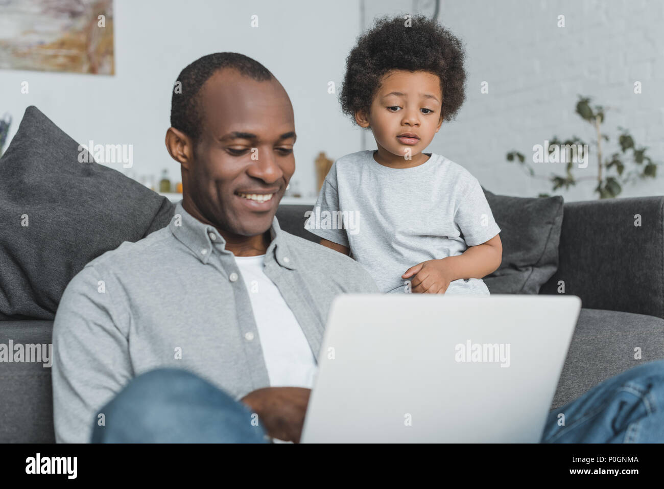 african american son watching how father using laptop at home Stock ...