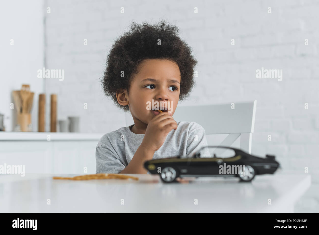 adorable african american boy eating crispy breadsticks at home Stock ...