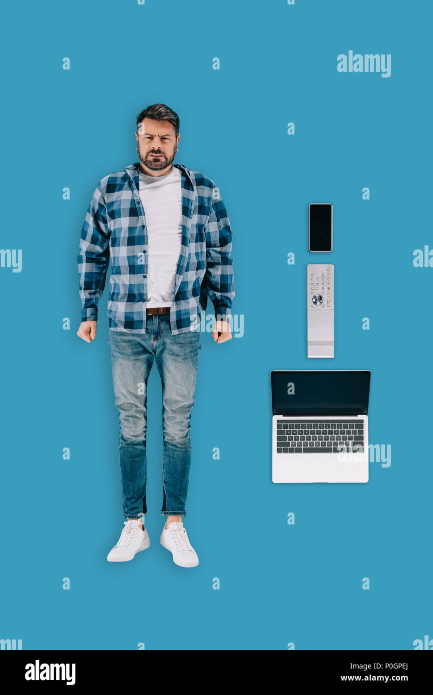 top view of stressed remote worker with smartphone, remote controller ...