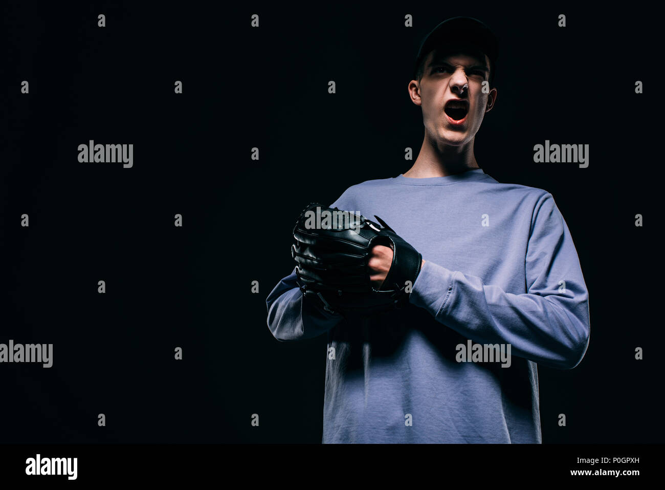 Screaming young man with baseball glove isolated on black Stock Photo ...