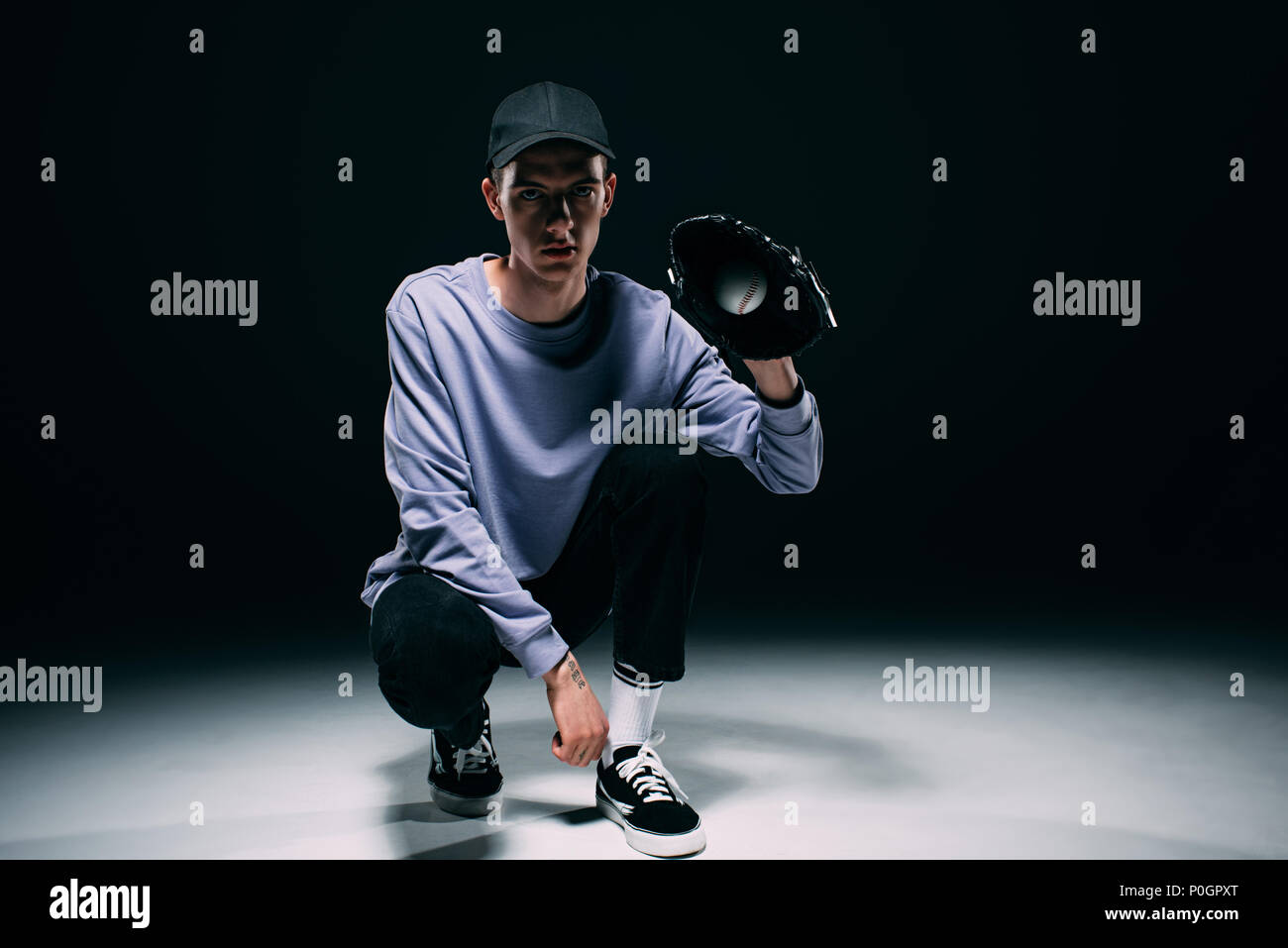 Handsome young man with baseball glove catching ball on dark background ...