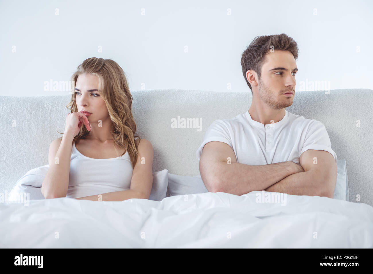 young dissatisfied couple lying in bed, relationship difficulties ...