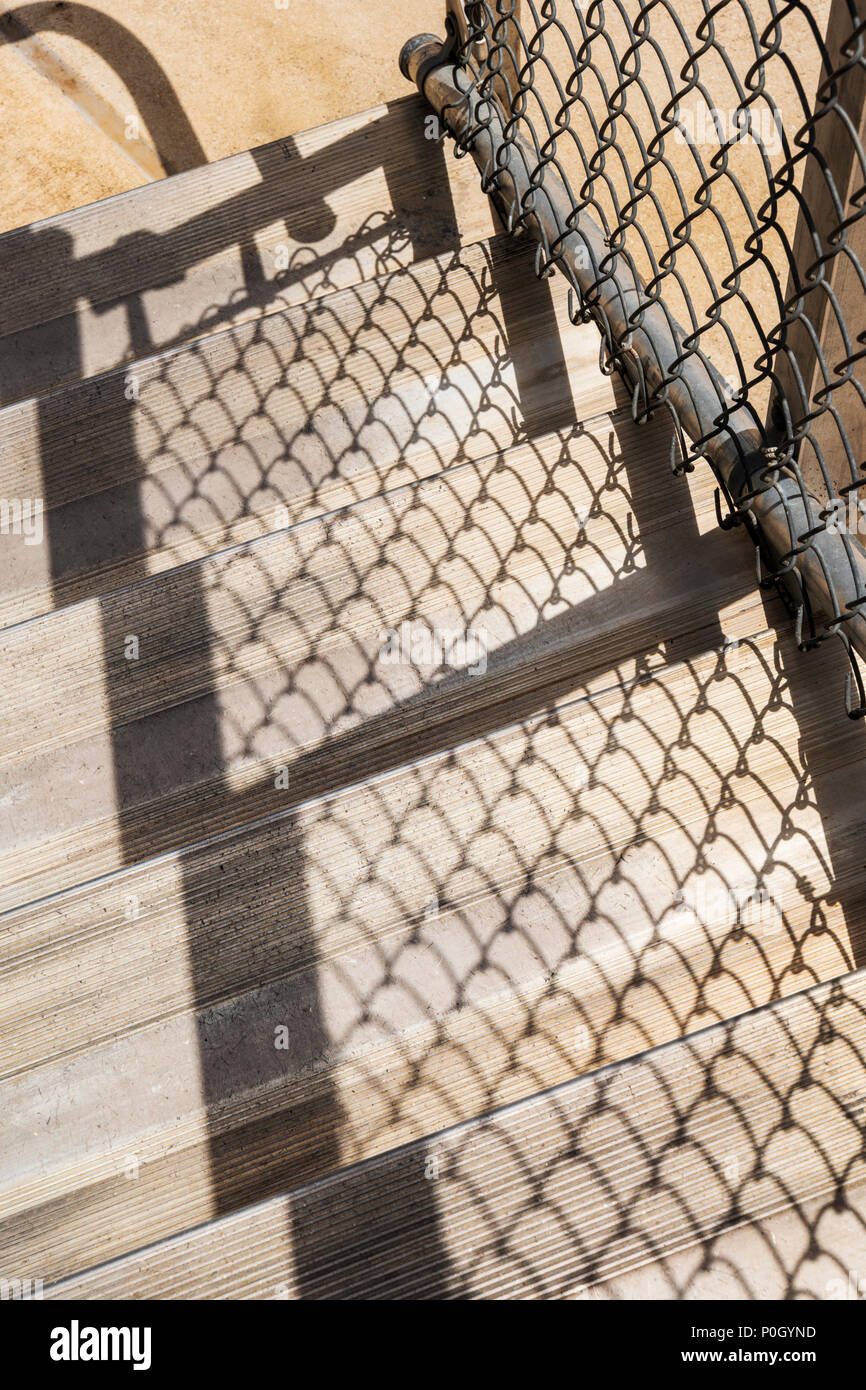 Cyclone fence casts graphic abstract shadows & patterns on cement ...