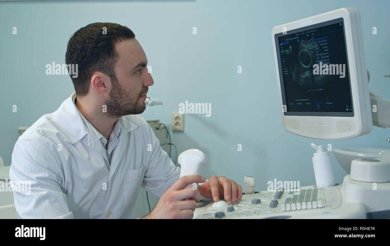 Concentrated male doctor looking at ultrasound scan results Stock Photo ...