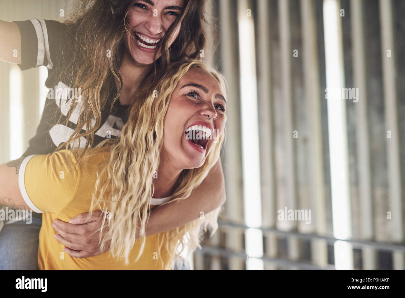 Laughing young woman being carried by her friend while having fun ...