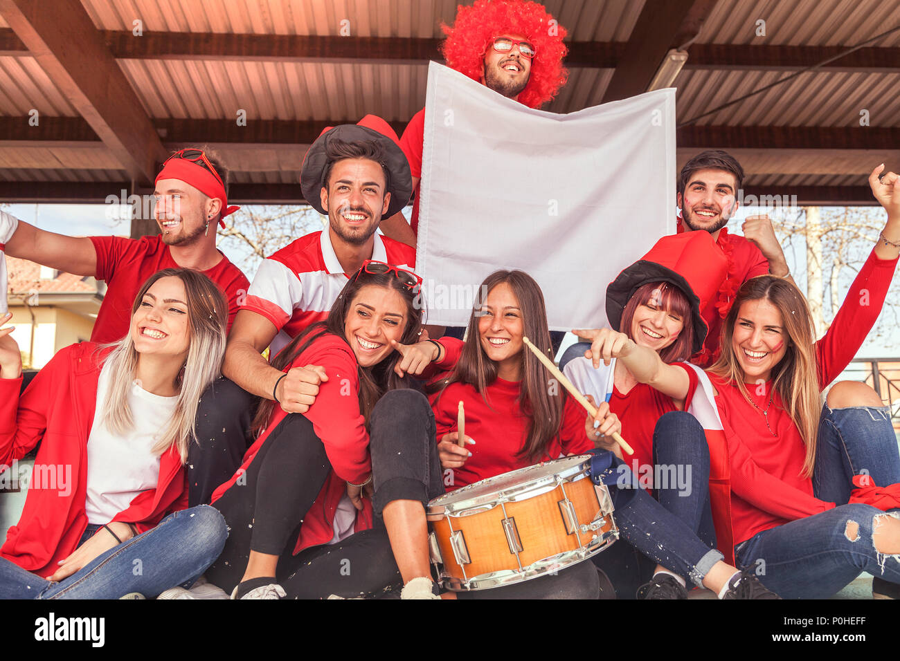 group of fans dressed in red color watching a sports event in the ...