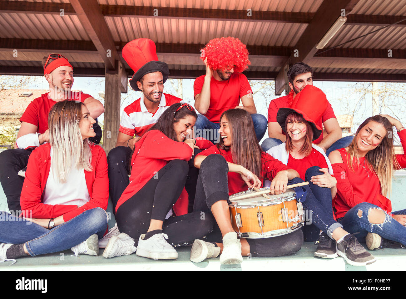 group of fans dressed in red color watching a sports event in the ...