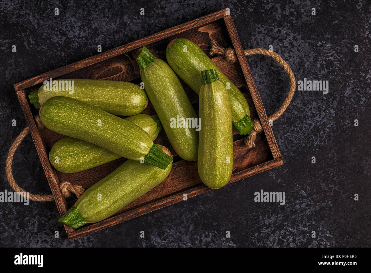 Fresh healthy green zucchini courgettes in brown wooden box, top view ...