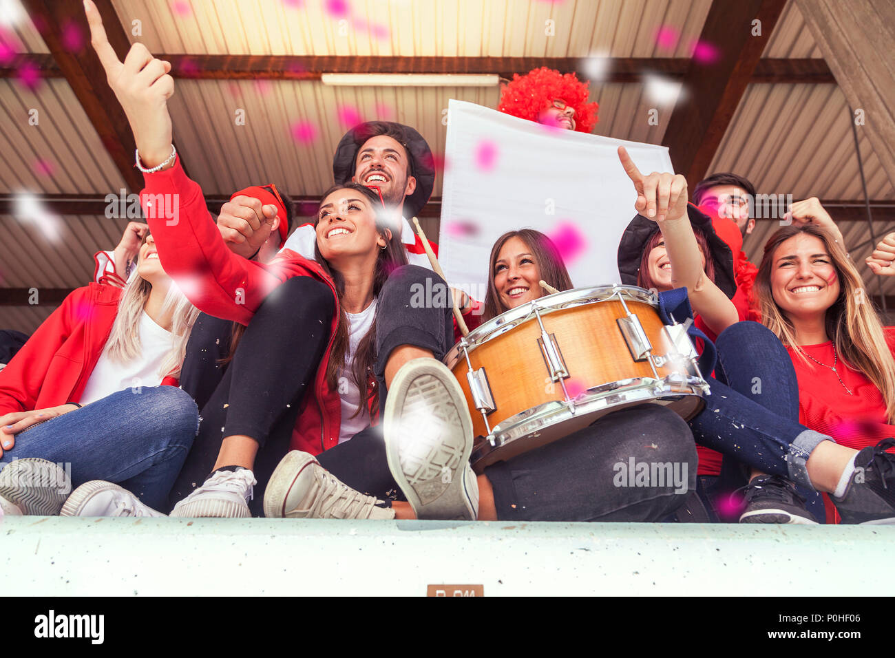 group of fans dressed in red color watching a sports event in the ...