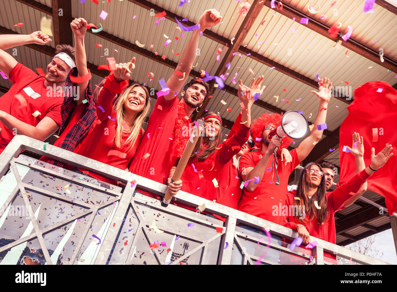 group of fans dressed in red color watching a sports event in the ...