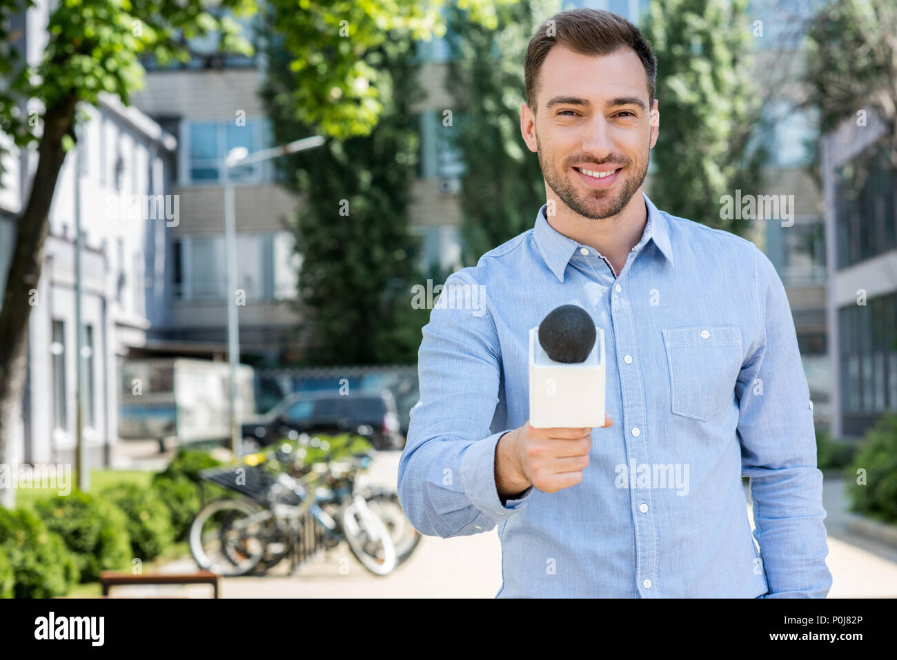 smiling male news reporter taking interview with microphone Stock Photo ...