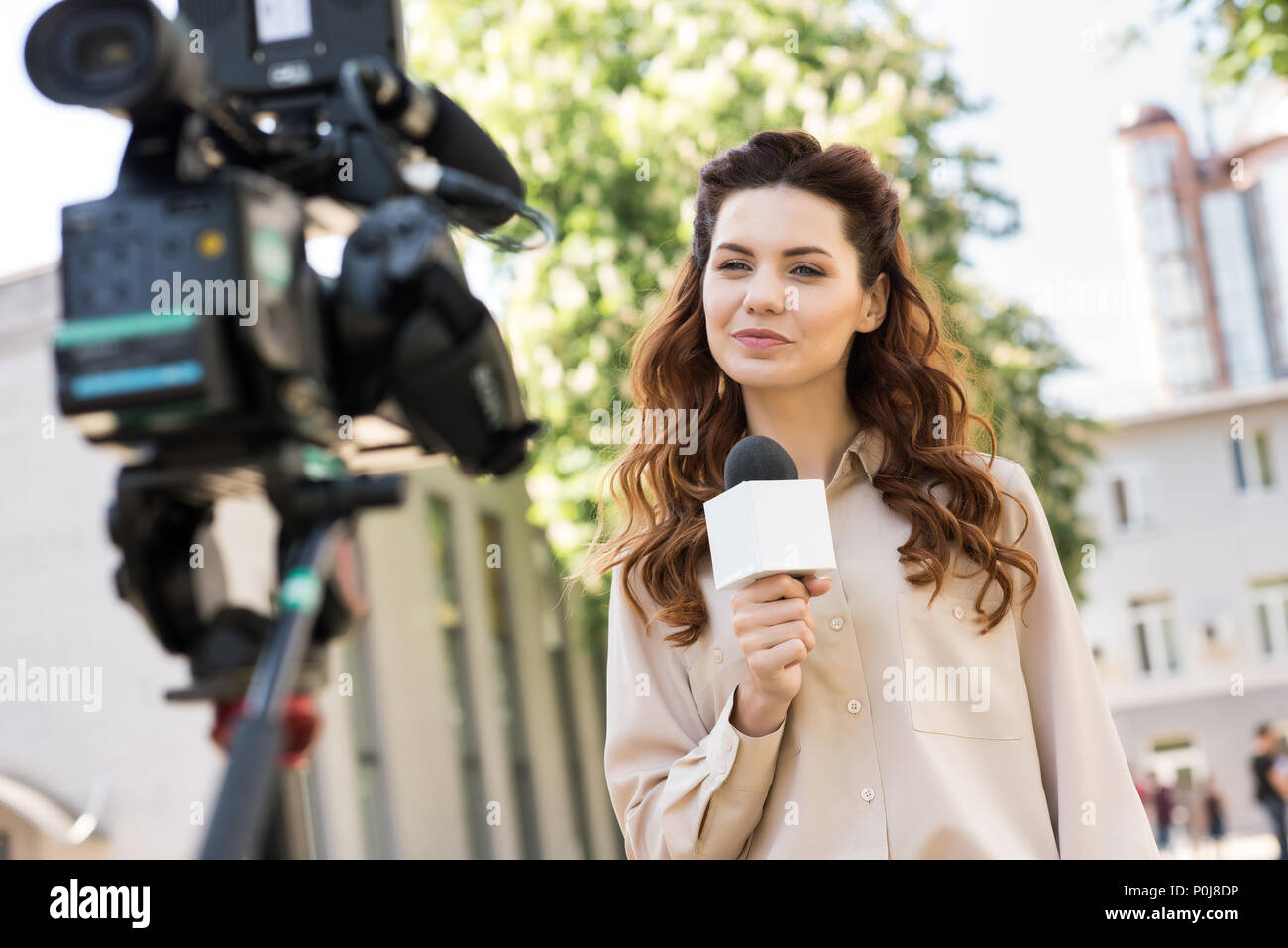 beautiful female journalist with microphone talking to digital video ...
