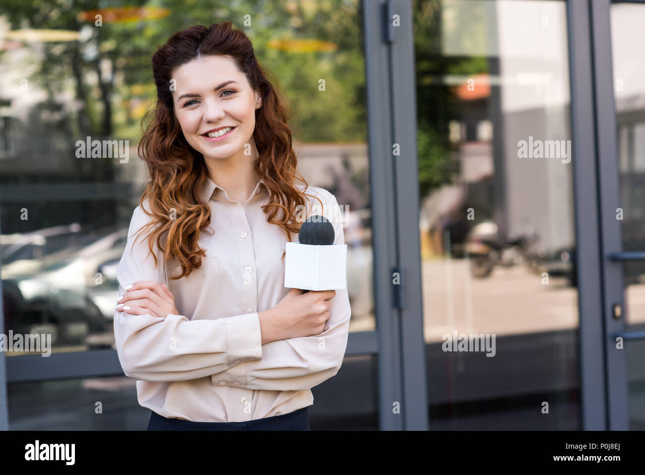 attractive female journalist holding microphone and looking at camera ...