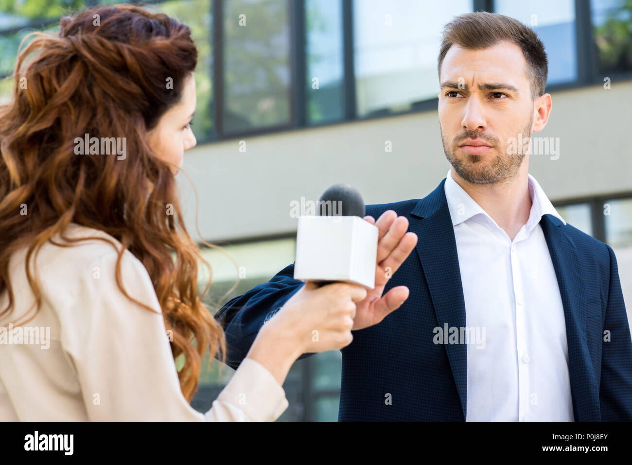 anchorwoman holding microphone while serious businessman refusing ...