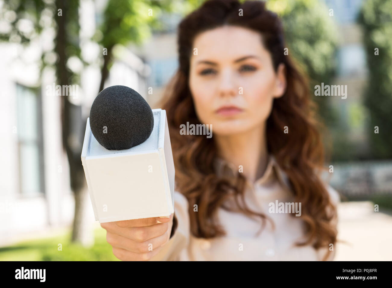 selective focus of serious anchorwoman taking interview with microphone ...