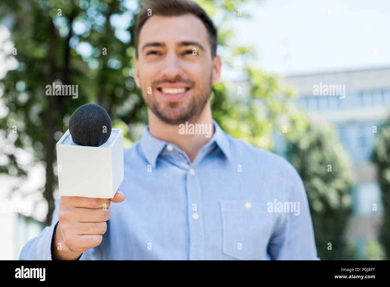 smiling anchorman taking interview with microphone Stock Photo - Alamy