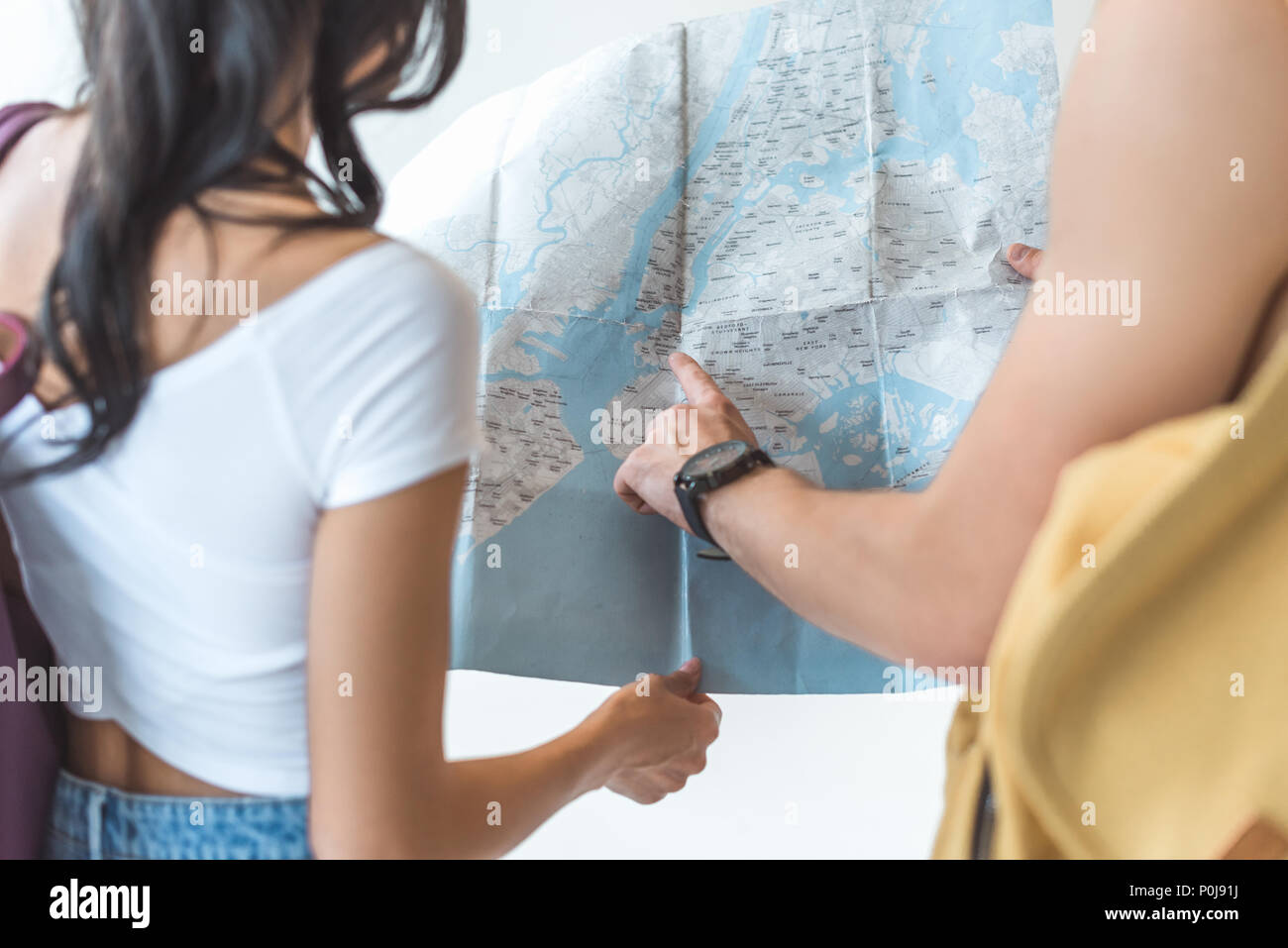 back view of tourists looking and pointing at map, isolated on white ...