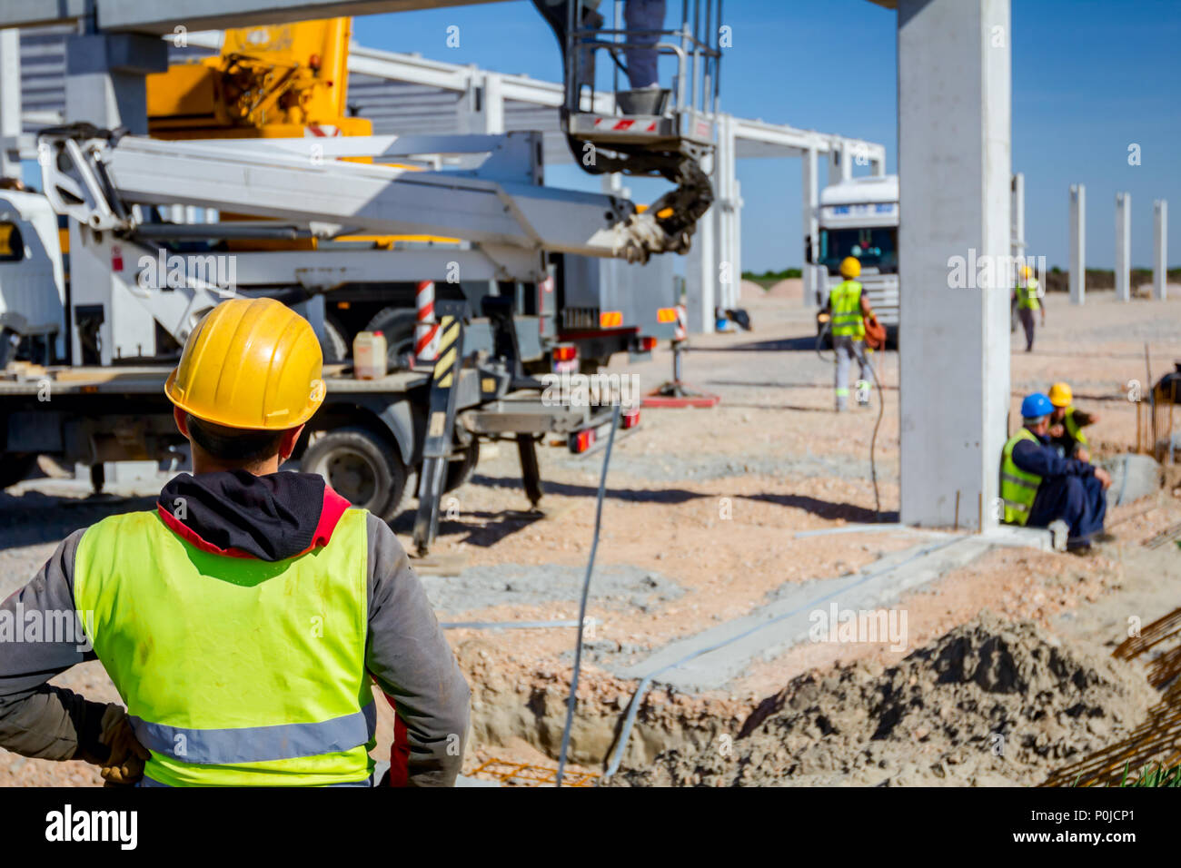 View from behind on construction worker with safety vest and yellow ...