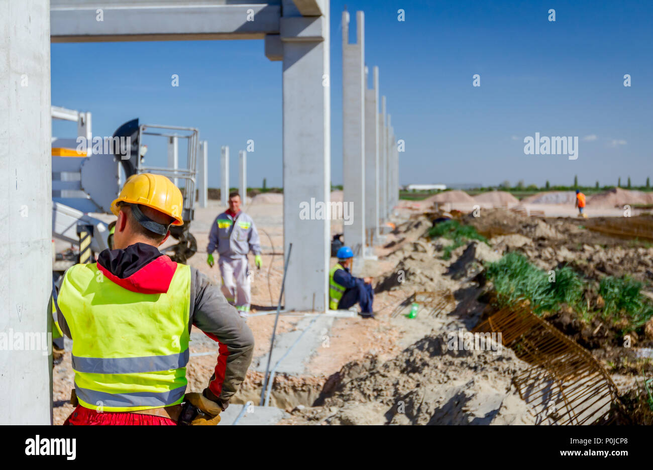 View from behind on construction worker with safety vest and yellow ...
