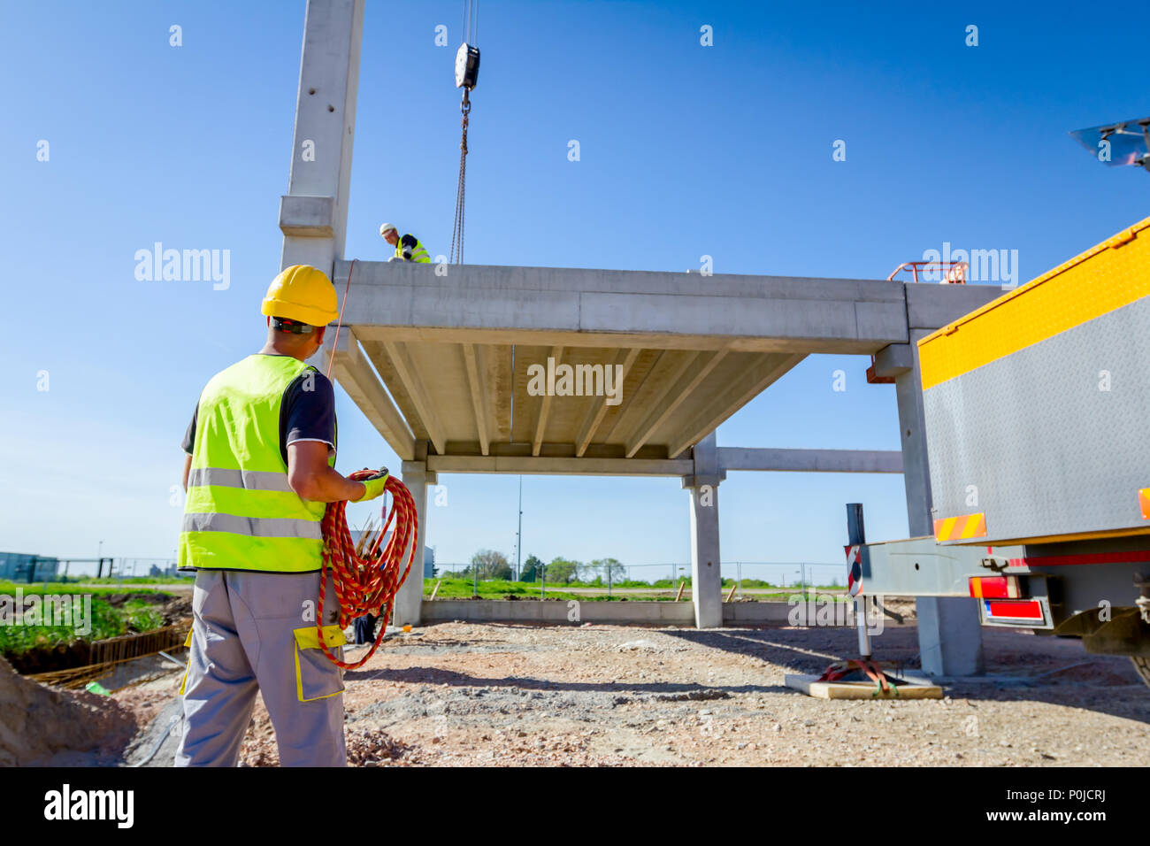 Worker is helping mobile crane with rope to manage concrete joist for ...