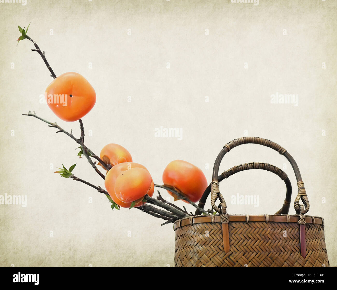 Persimmons in the basket on old paper background Stock Photo - Alamy
