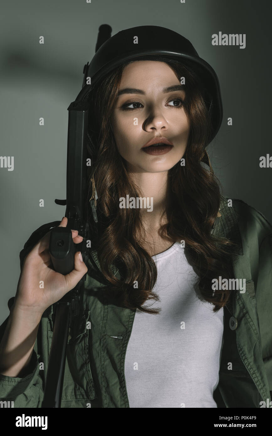beautiful soldier posing in military helmet with rifle, on grey with ...
