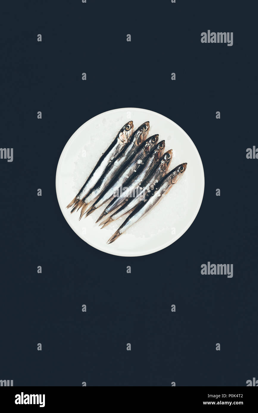 Top view of salted pile of fish in plate isolated on black Stock Photo ...