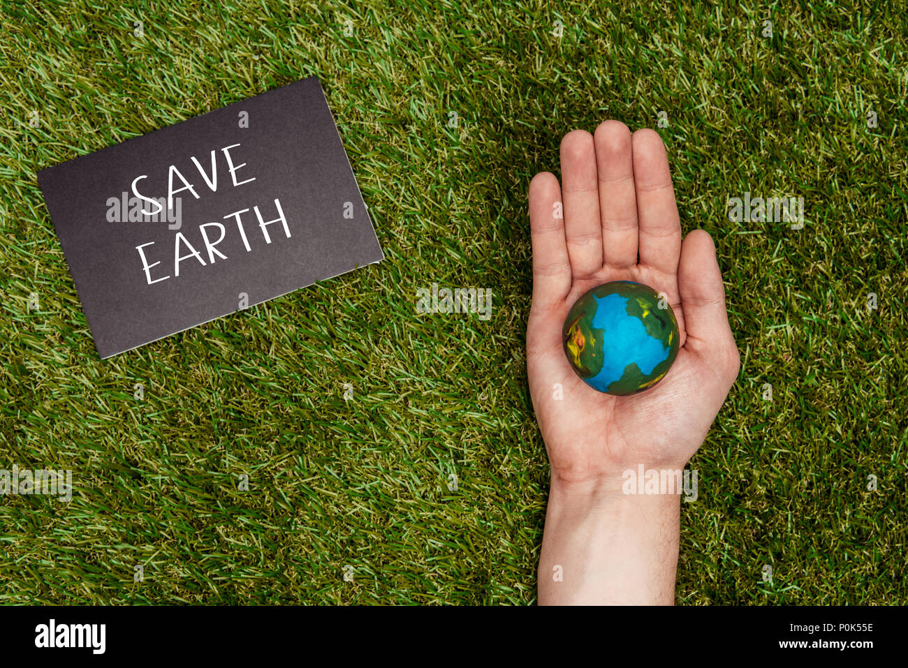 cropped image of man holding earth model in hand with sign save earth ...