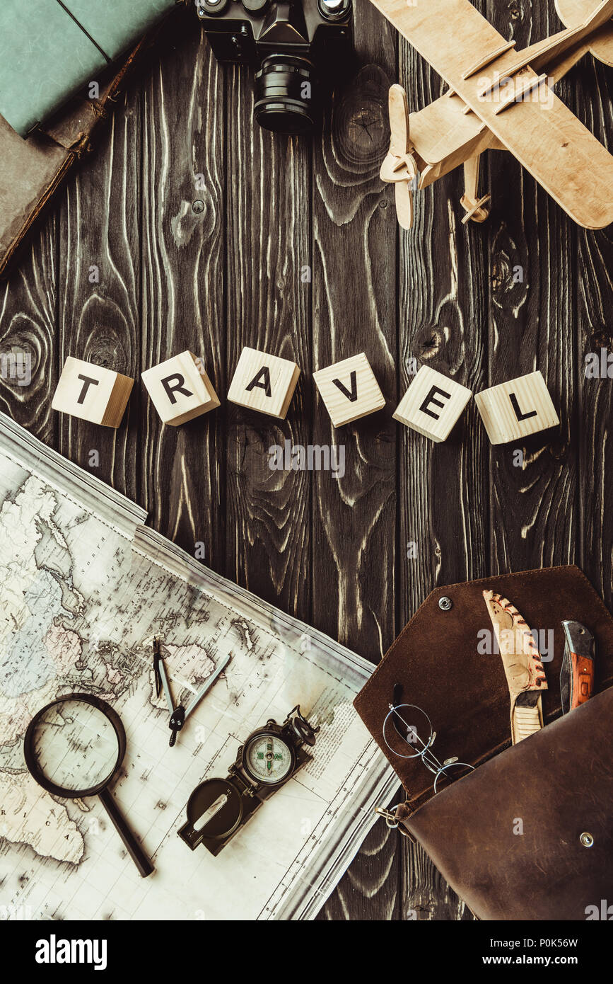 top view of arranged wooden blocks in travel word with map, retro photo ...