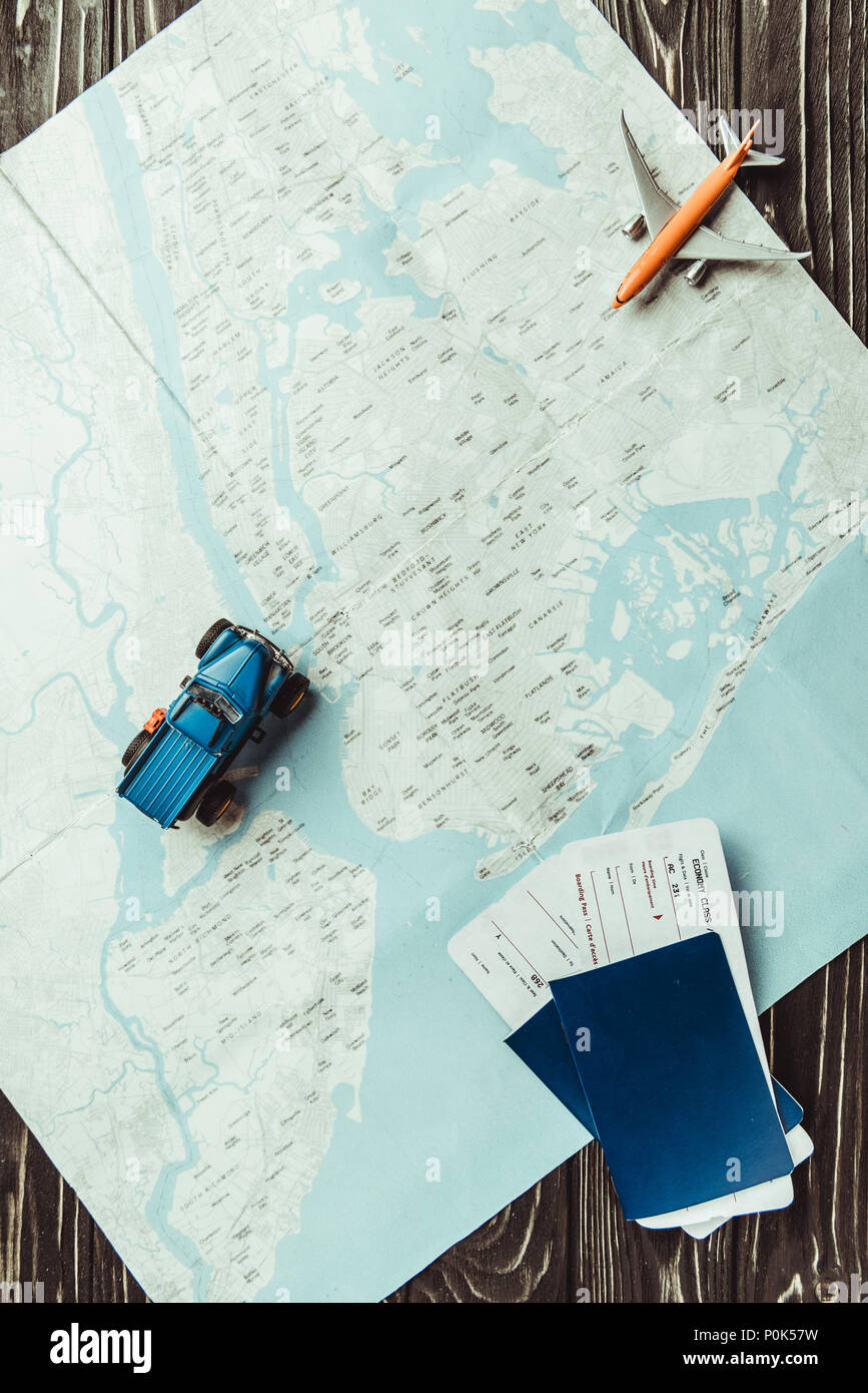 flat lay with map, toys, passports and tickets on dark wooden tabletop ...