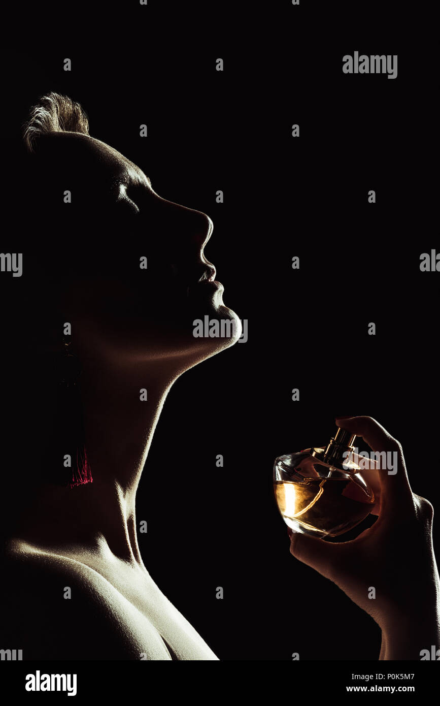 silhouette of sensual woman spraying perfume on neck, isolated on black ...