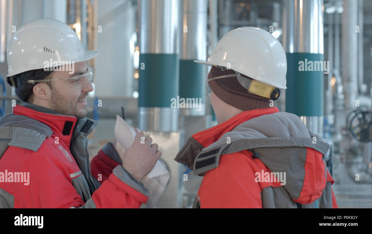 Two chemical factory workers having conversation in plant Stock Photo ...