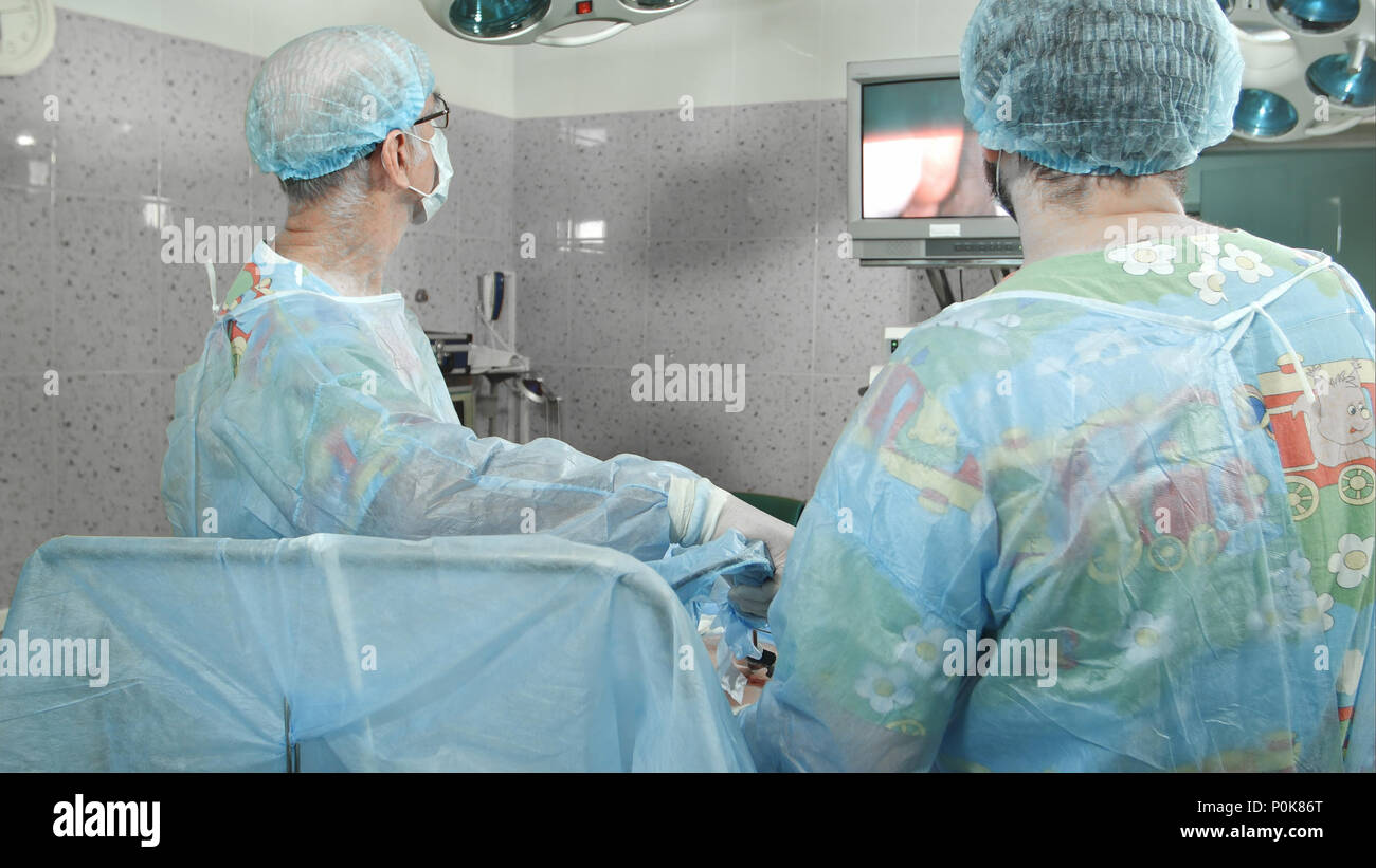 Surgeons follow the laparoscopic surgery, looking at screen Stock Photo ...