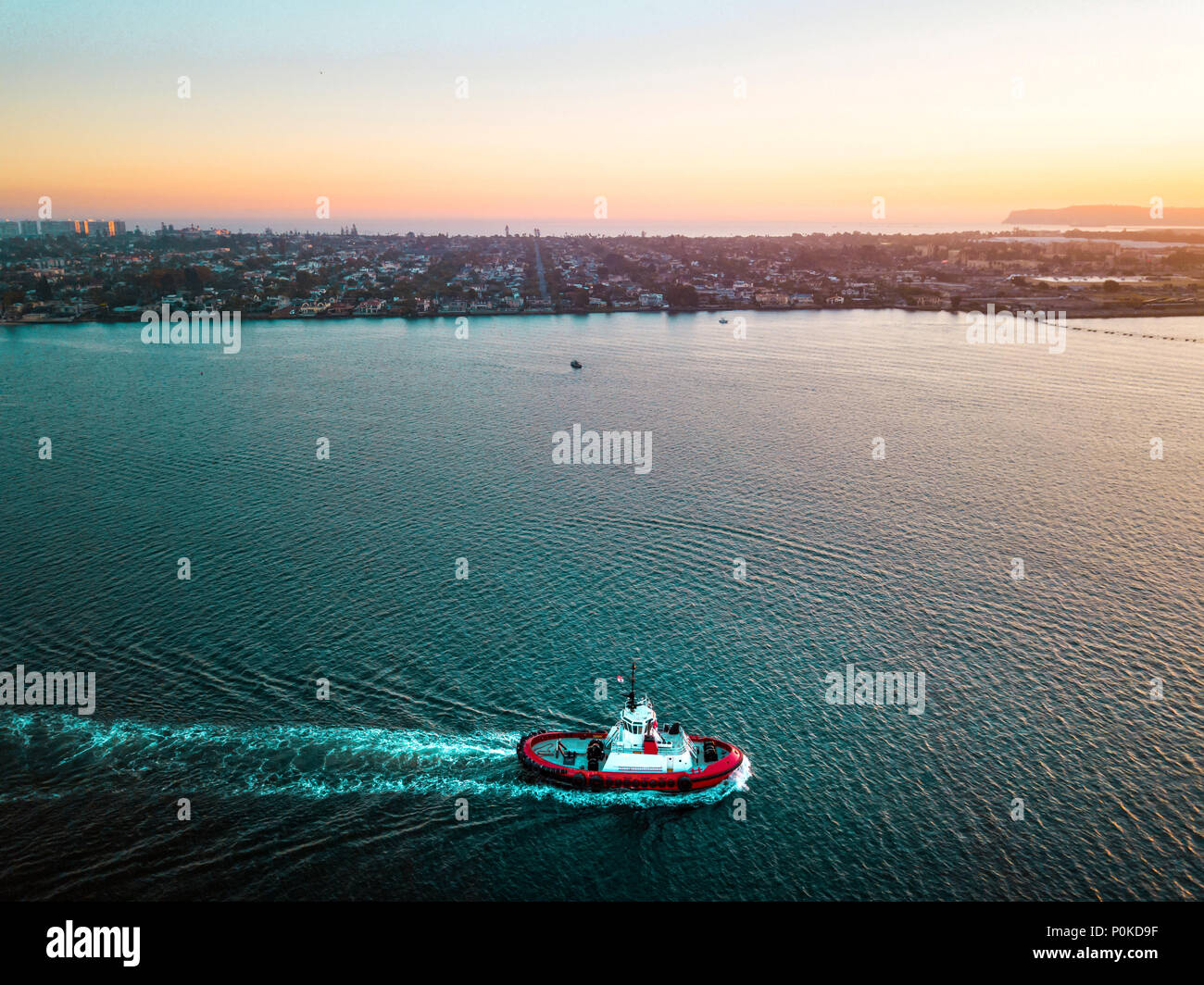 Aerial photo of a small tugboat sailing in San Diego bay area at sunset ...