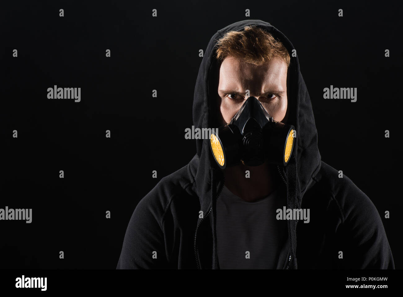 Man in black hood wearing protective filter mask isolated on black ...