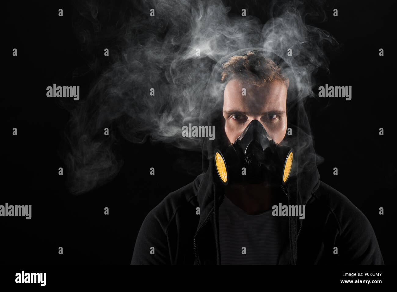 Man in black hood wearing protective filter mask surrounded by clouds ...