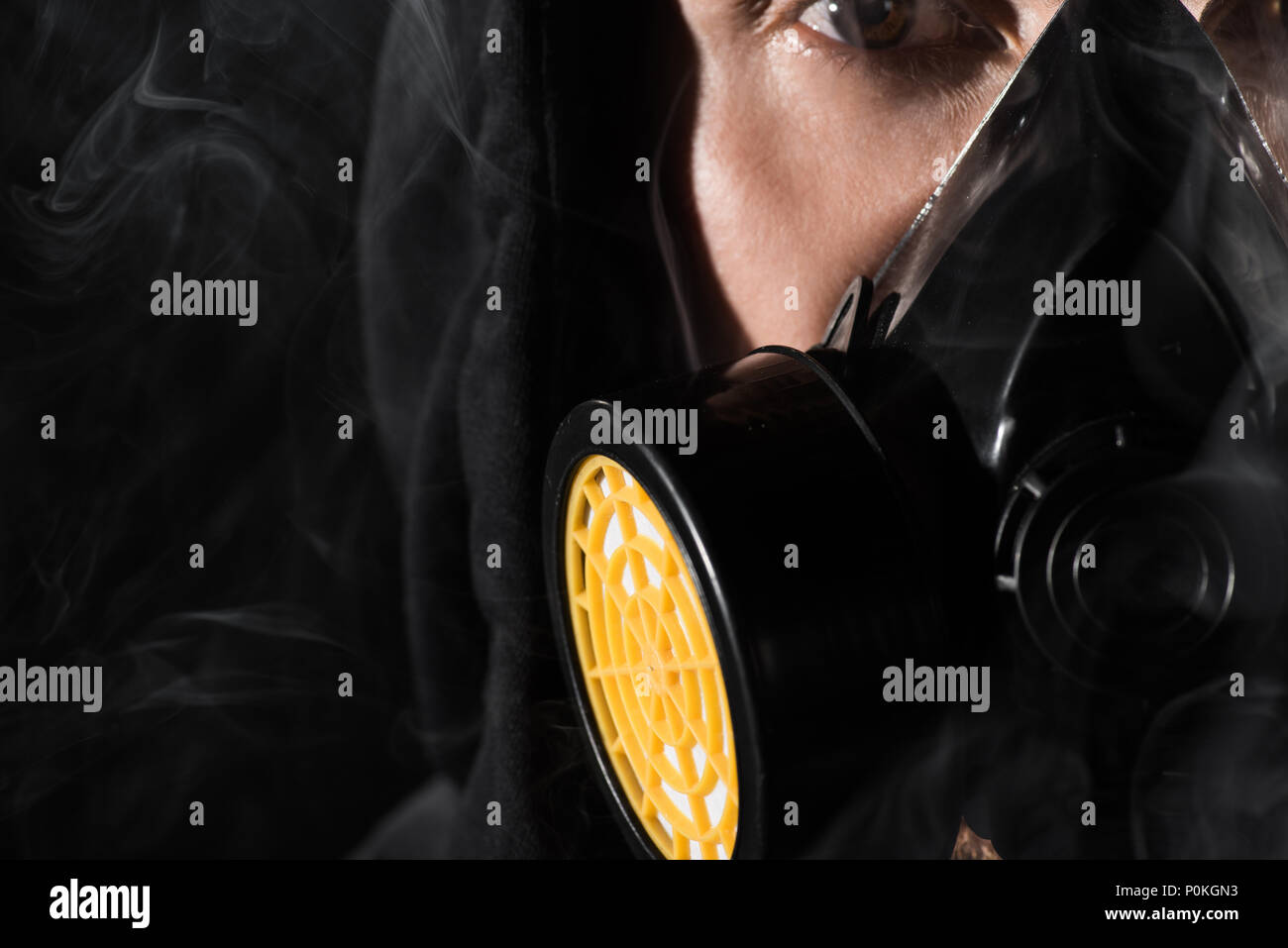 Man in black hood wearing protective filter mask surrounded by clouds ...