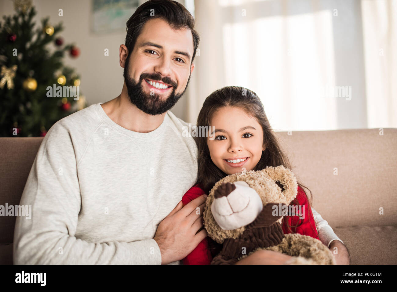 father hugging daughter with teddy bear and looking at camera Stock ...