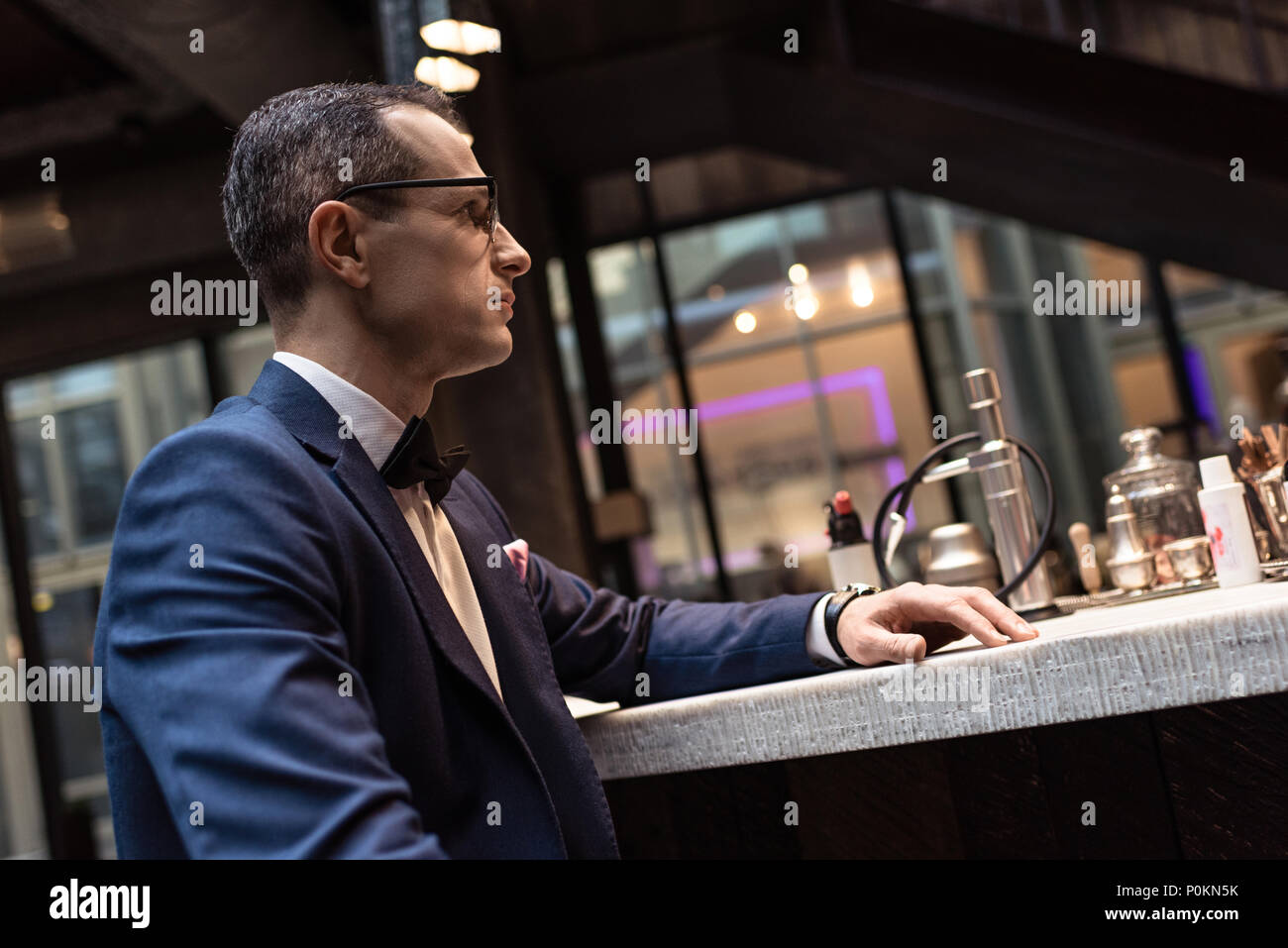 handsome man in stylish suit sitting at bar counter of luxury ...